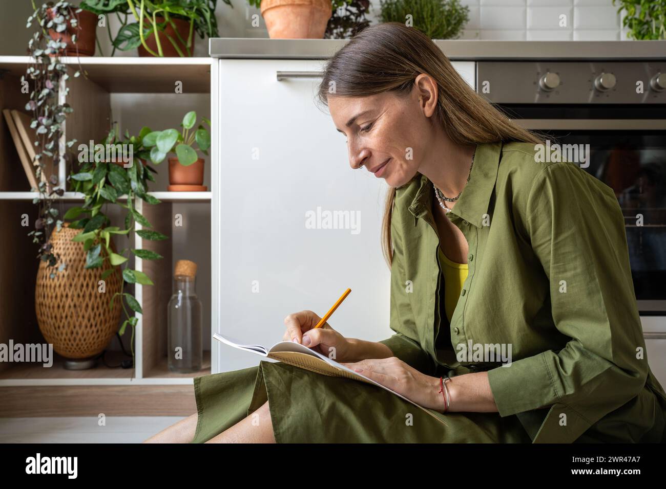 Relaxed woman reflects on thoughts, writing in notebook after therapy ...