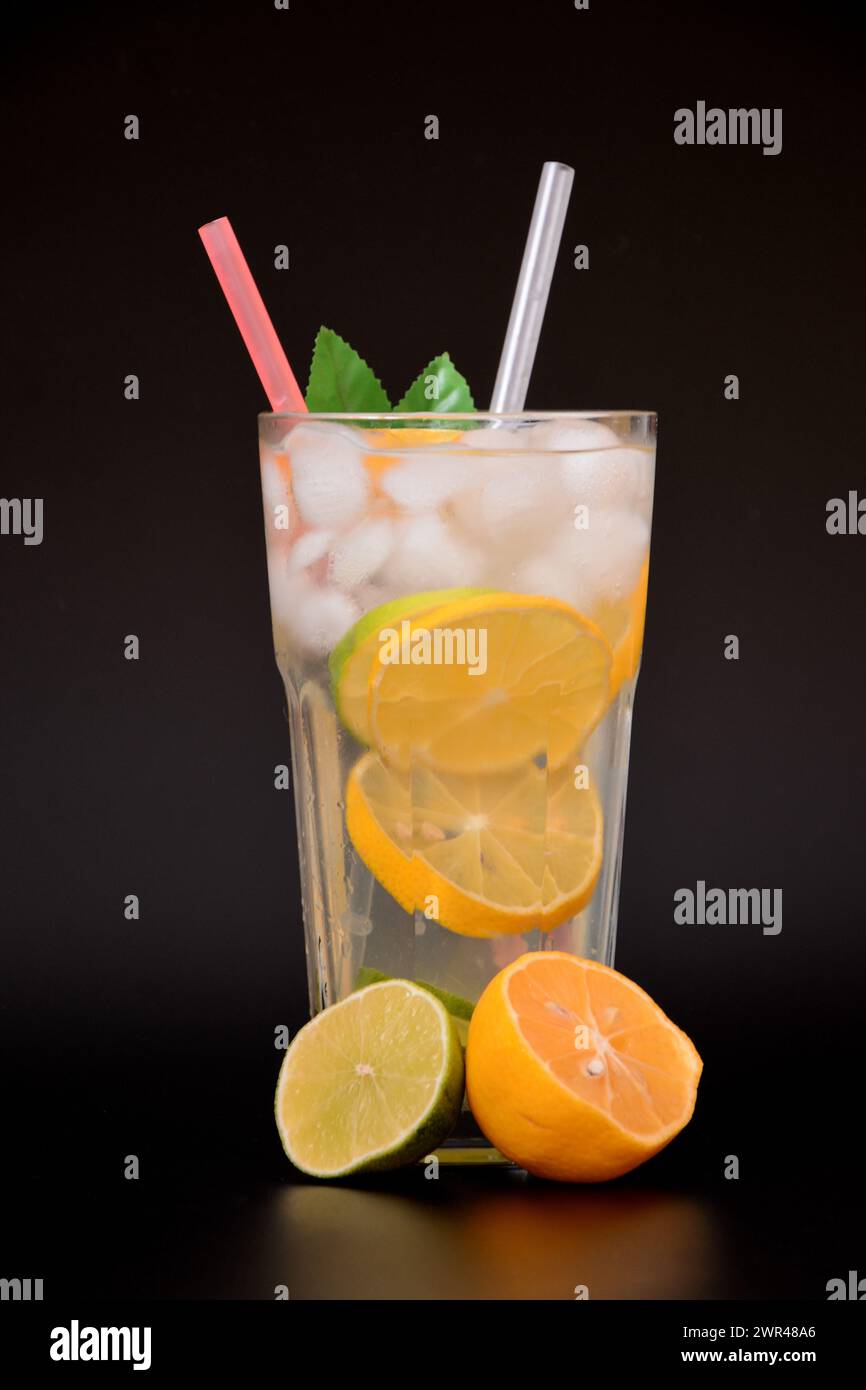 A tall glass of refreshing lemonade with ice and citrus fruit pieces on ...
