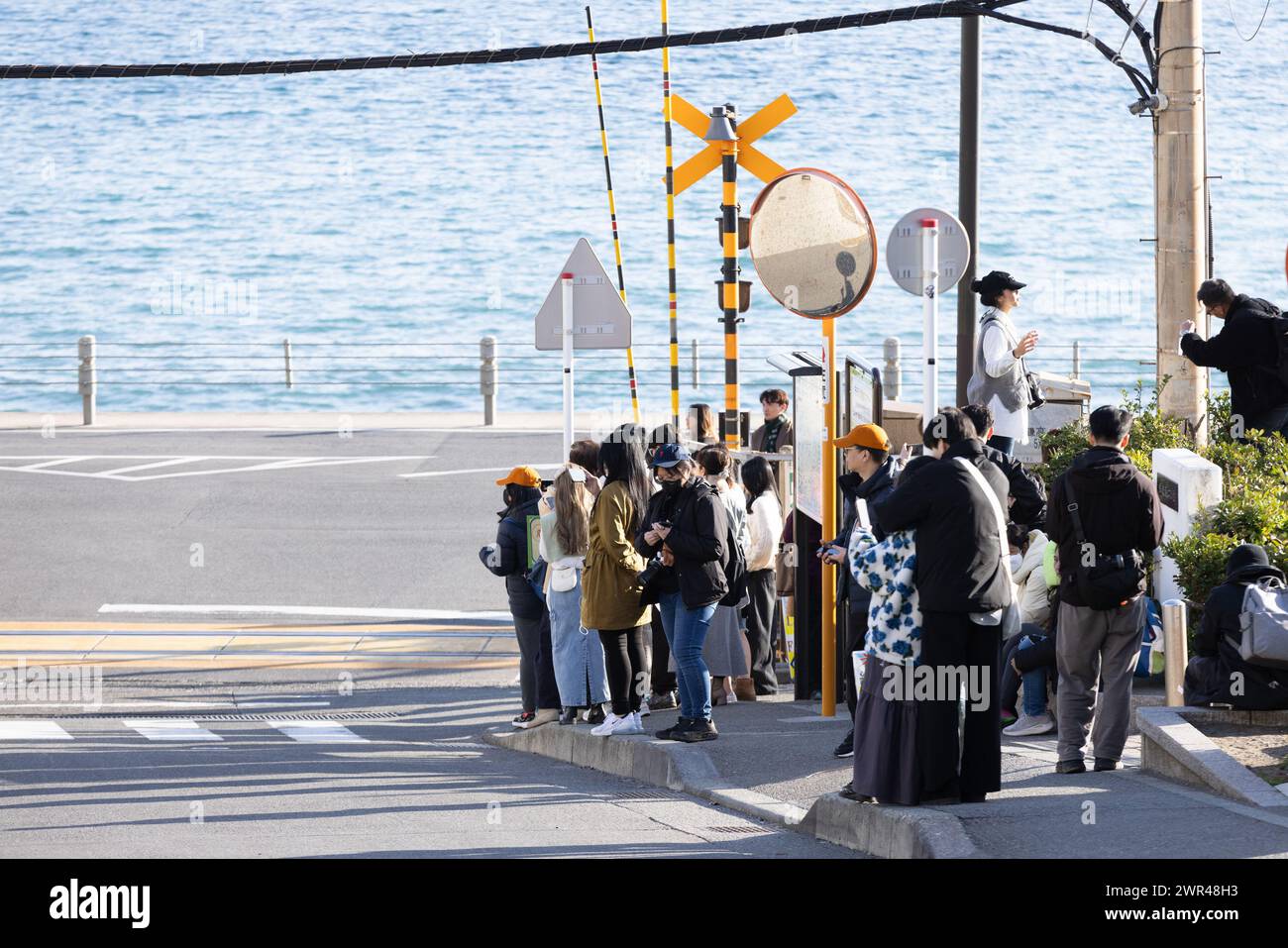 Tourists are taking photos around the railroad crossing at Enoden's ...