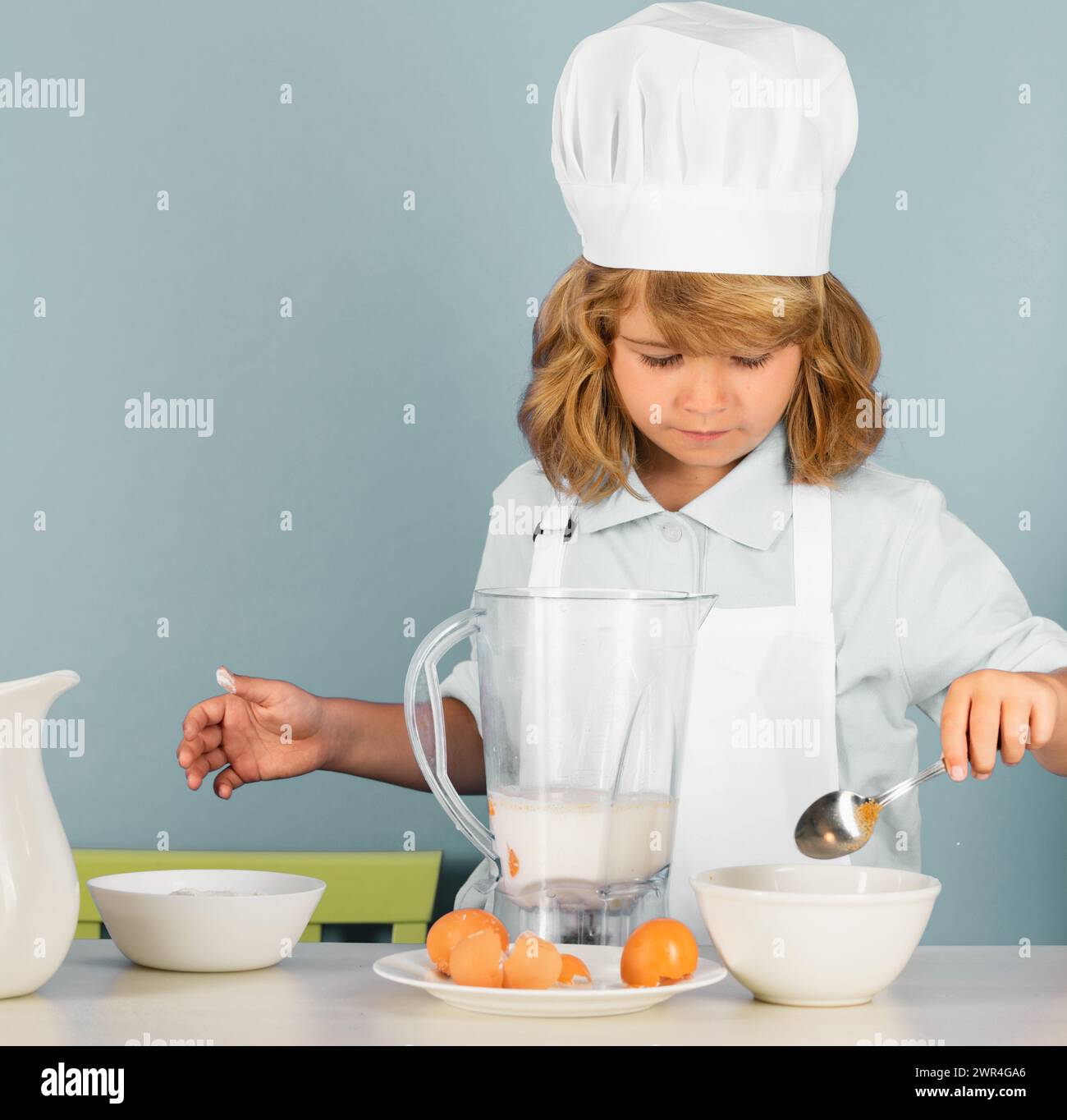 Child chef cook prepares food on isolated grey studio background. Kids ...