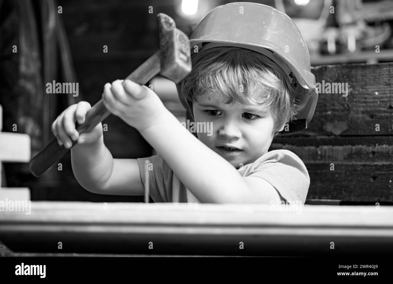 Kid in hard hat holding wooden plank and hammer. Child engineer with ...