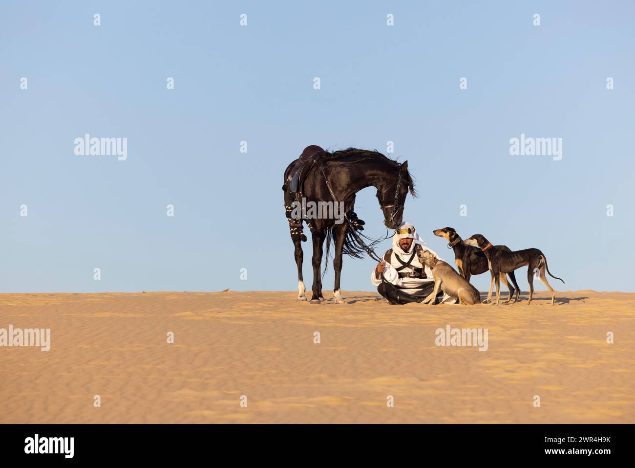 Man in traditional Saudi Arabian clothing in a desert with a black ...