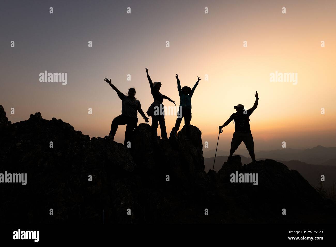 Silhouettes of a group of successful climbers on the top of a mountain ...