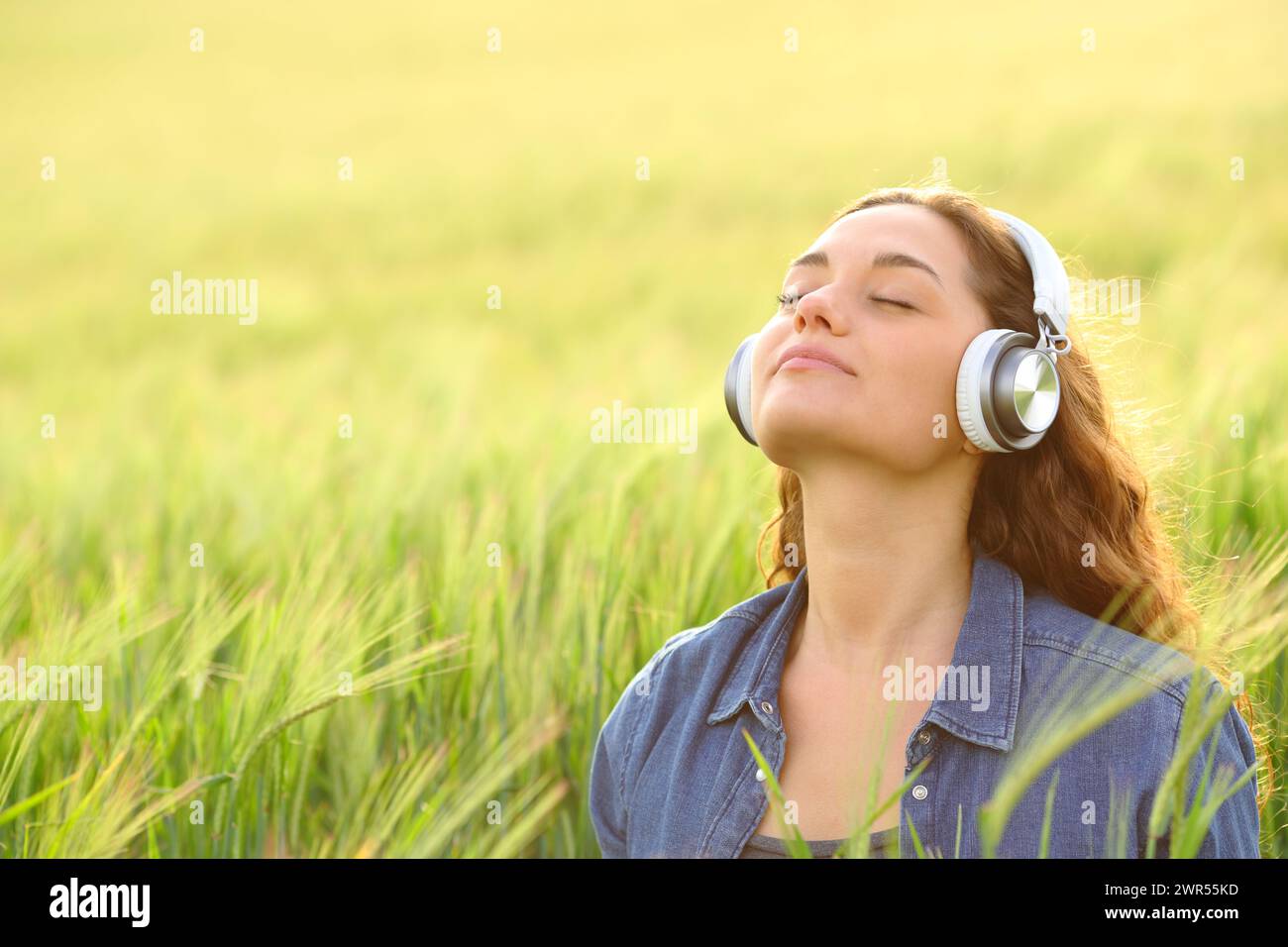 Woman wearing headphone meditating listening guided tutorial in nature ...