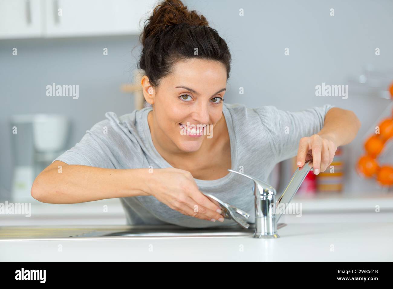 young woman using tap in kitchen Stock Photo - Alamy