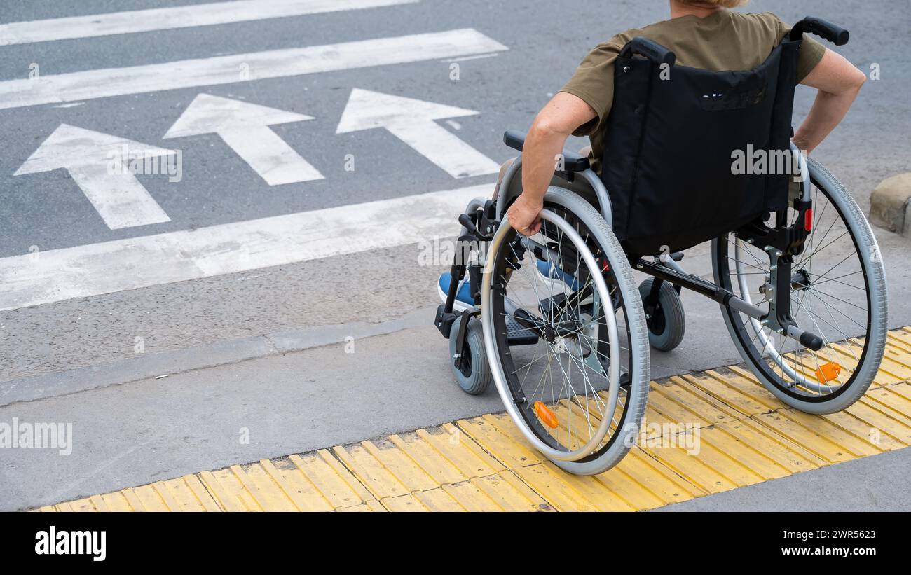 Rear view of an elderly Caucasian woman in a wheelchair crosses the ...