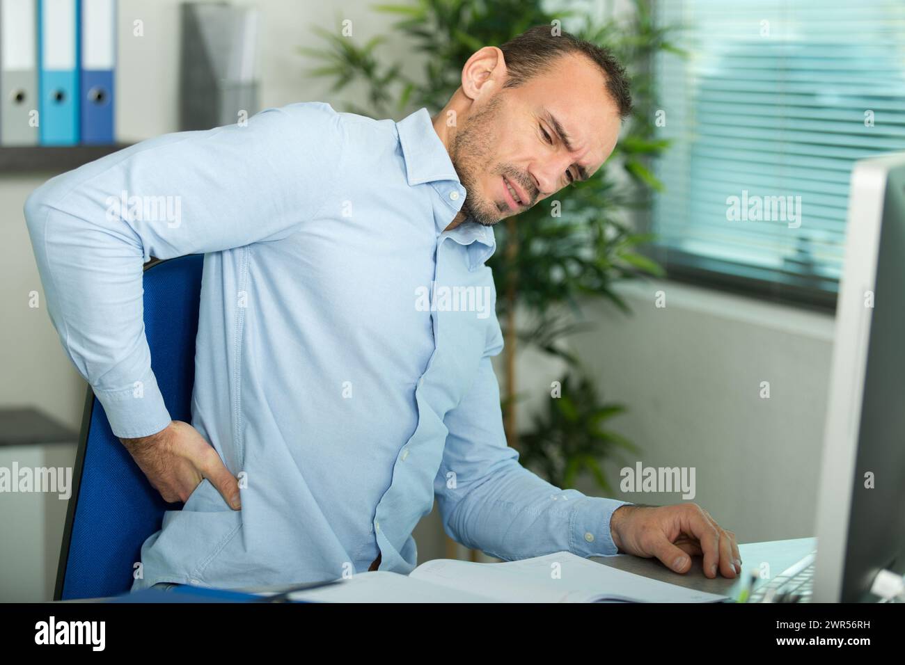 man at office desk stretching his aching back Stock Photo - Alamy