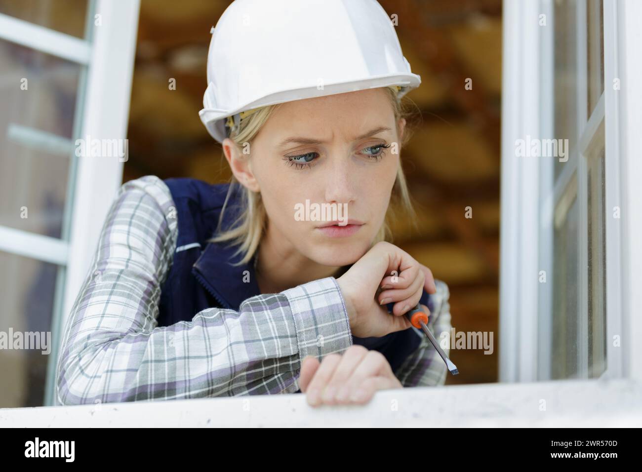 focused female construction worker using screwdriver on window frame ...