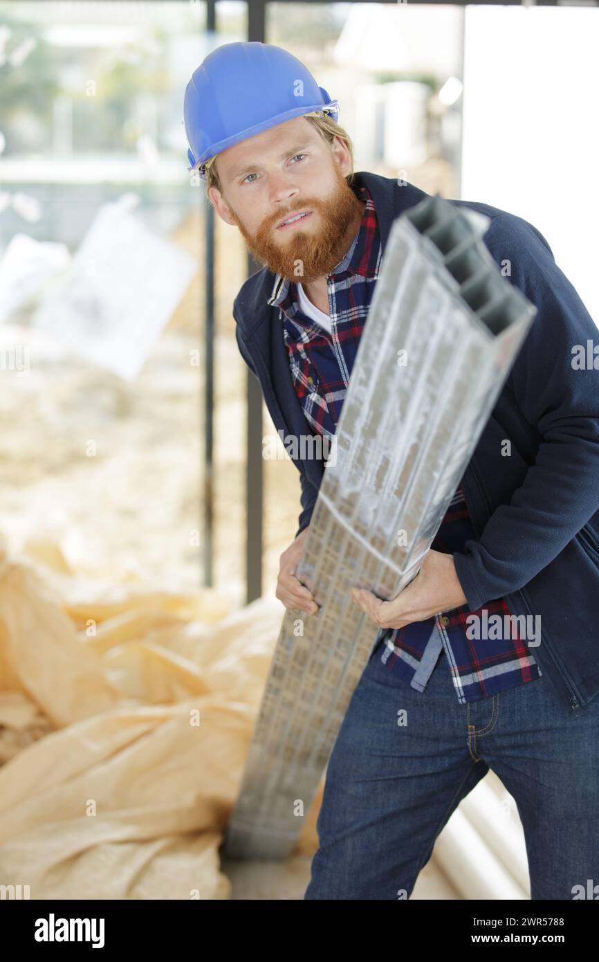 workman carrying metal frame Stock Photo - Alamy