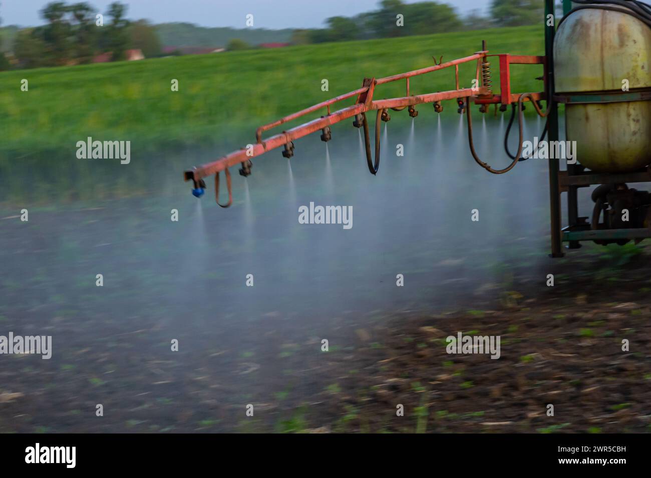 Tractor spraying pesticides on vegetable field with sprayer at spring ...