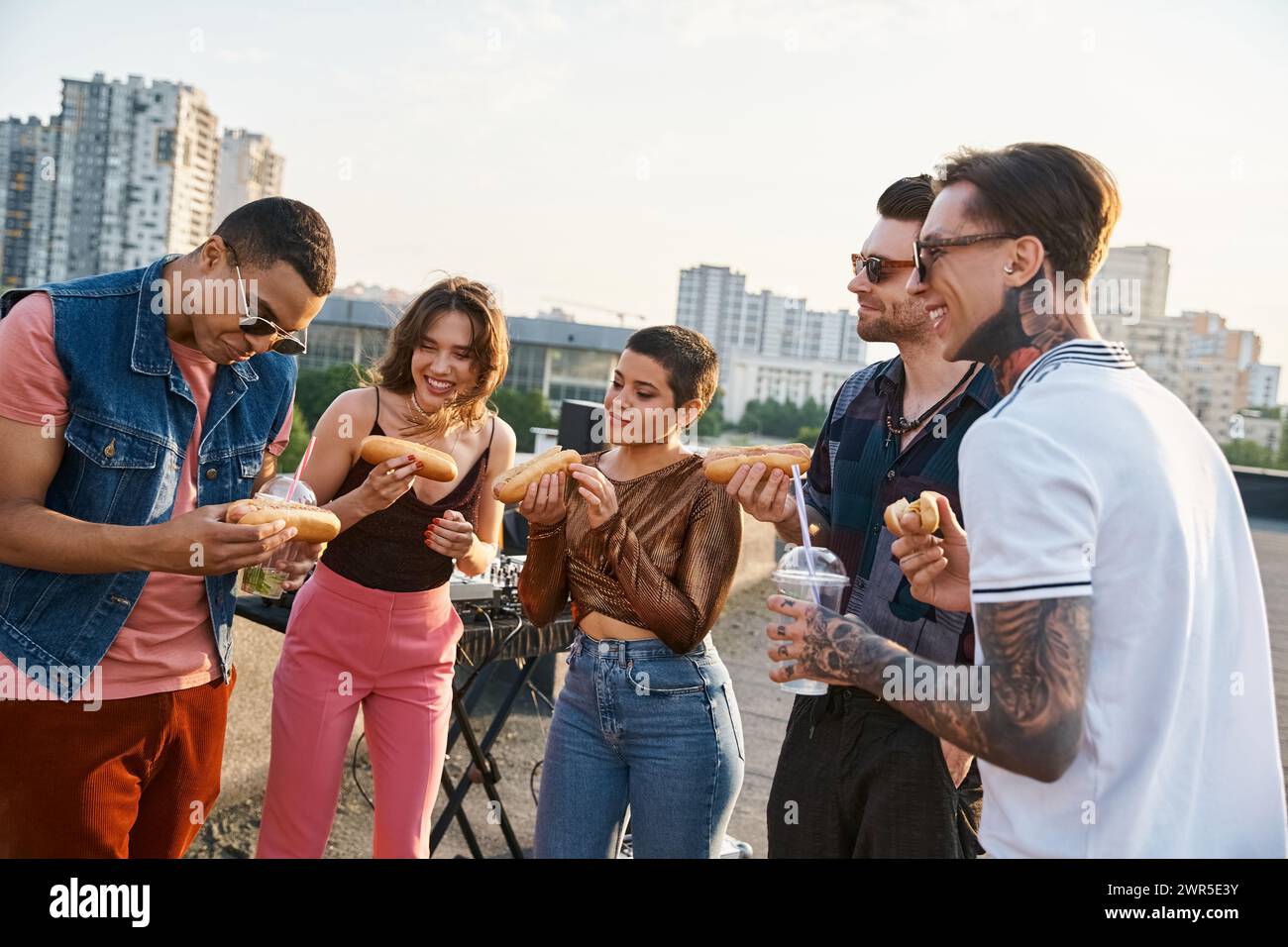 good looking jolly multicultural friends in urban outfits eating tasty ...