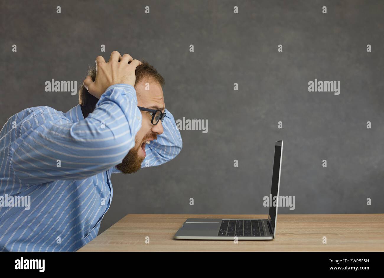 Desperate office worker looking at error message on screen of his ...