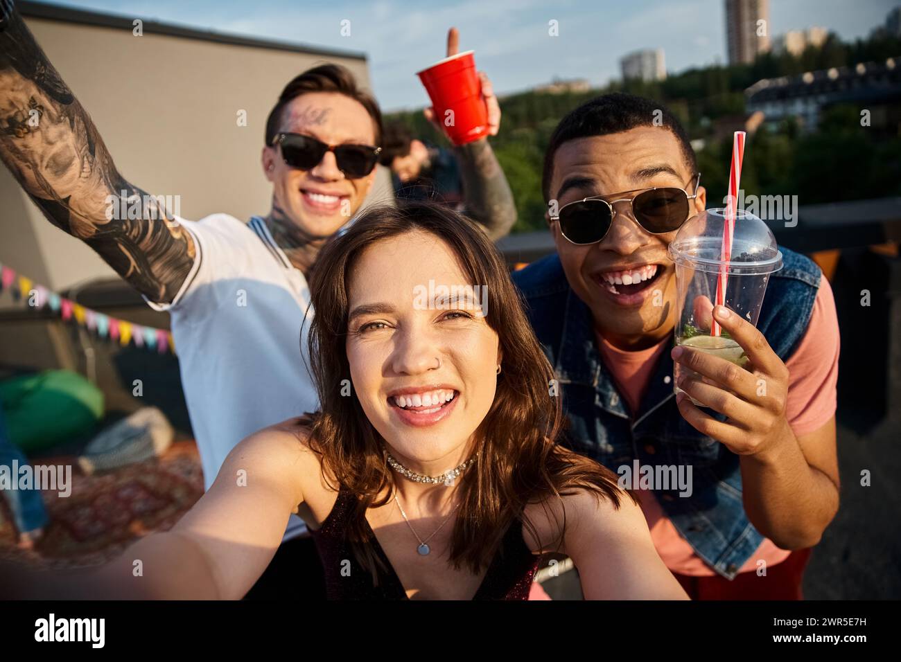 cheerful multicultural friends holding cocktails in hands and having ...