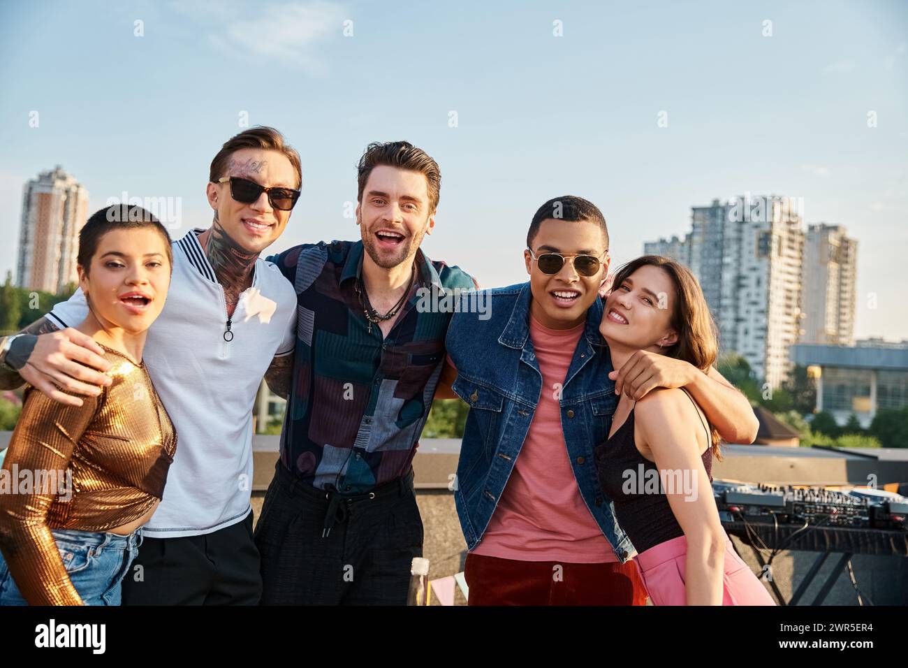 good looking jolly multiracial friends posing together on rooftop and ...