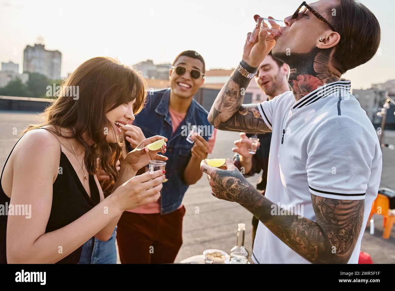 jolly multicultural people in vibrant clothes enjoying tequila with ...