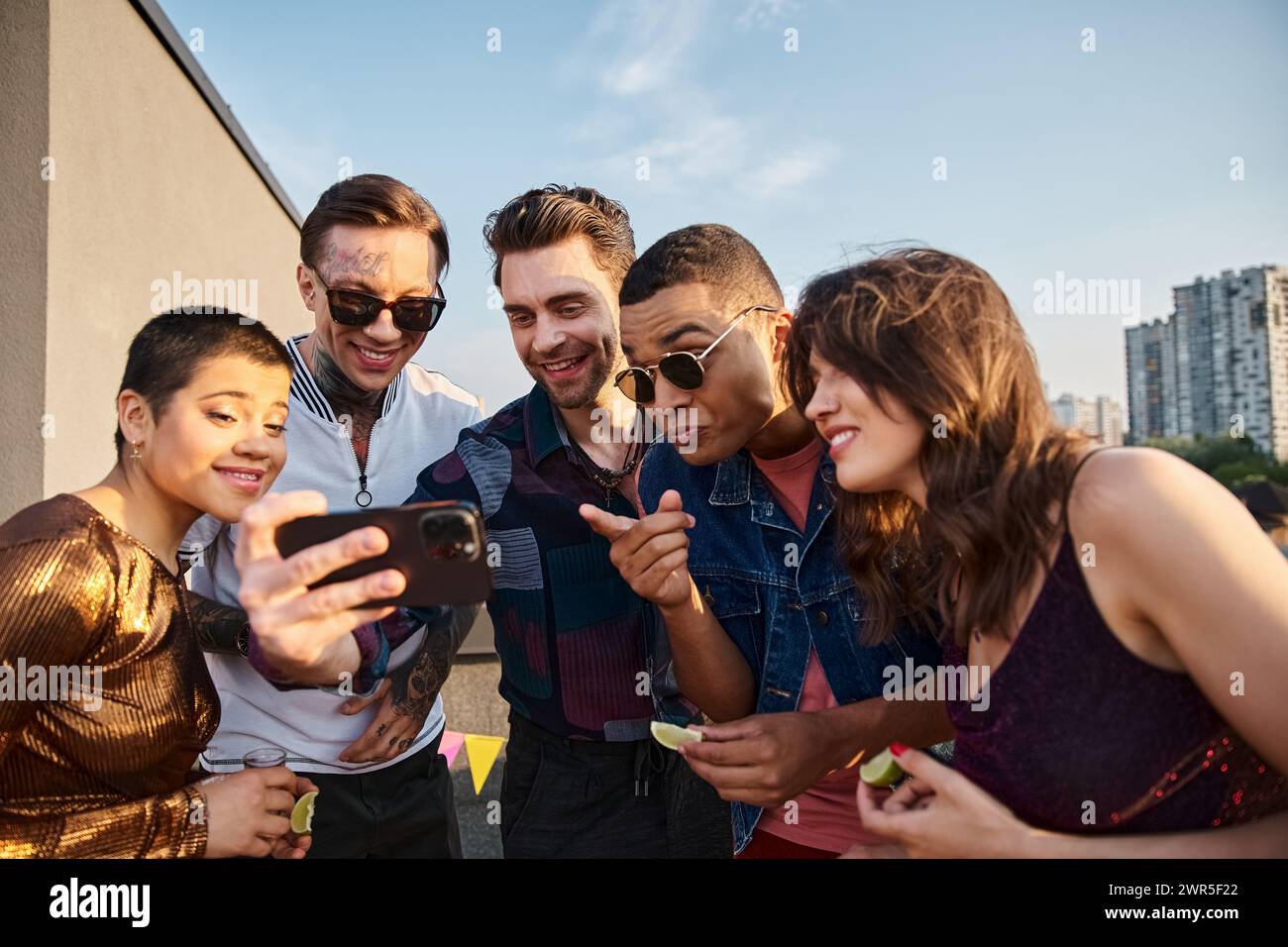 multiracial joyful people in casual clothes watching photos at ...