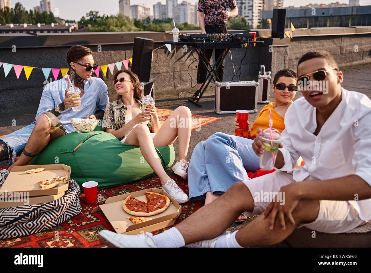 joyful multicultural friends with glasses sitting on rooftop with ...