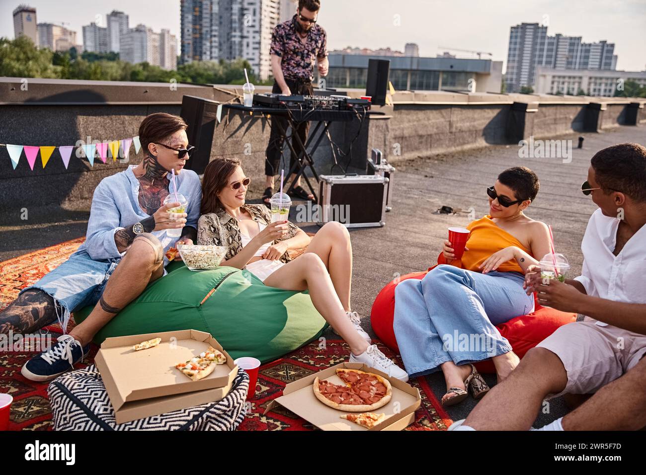 cheerful interracial friends with glasses sitting on rooftop with ...