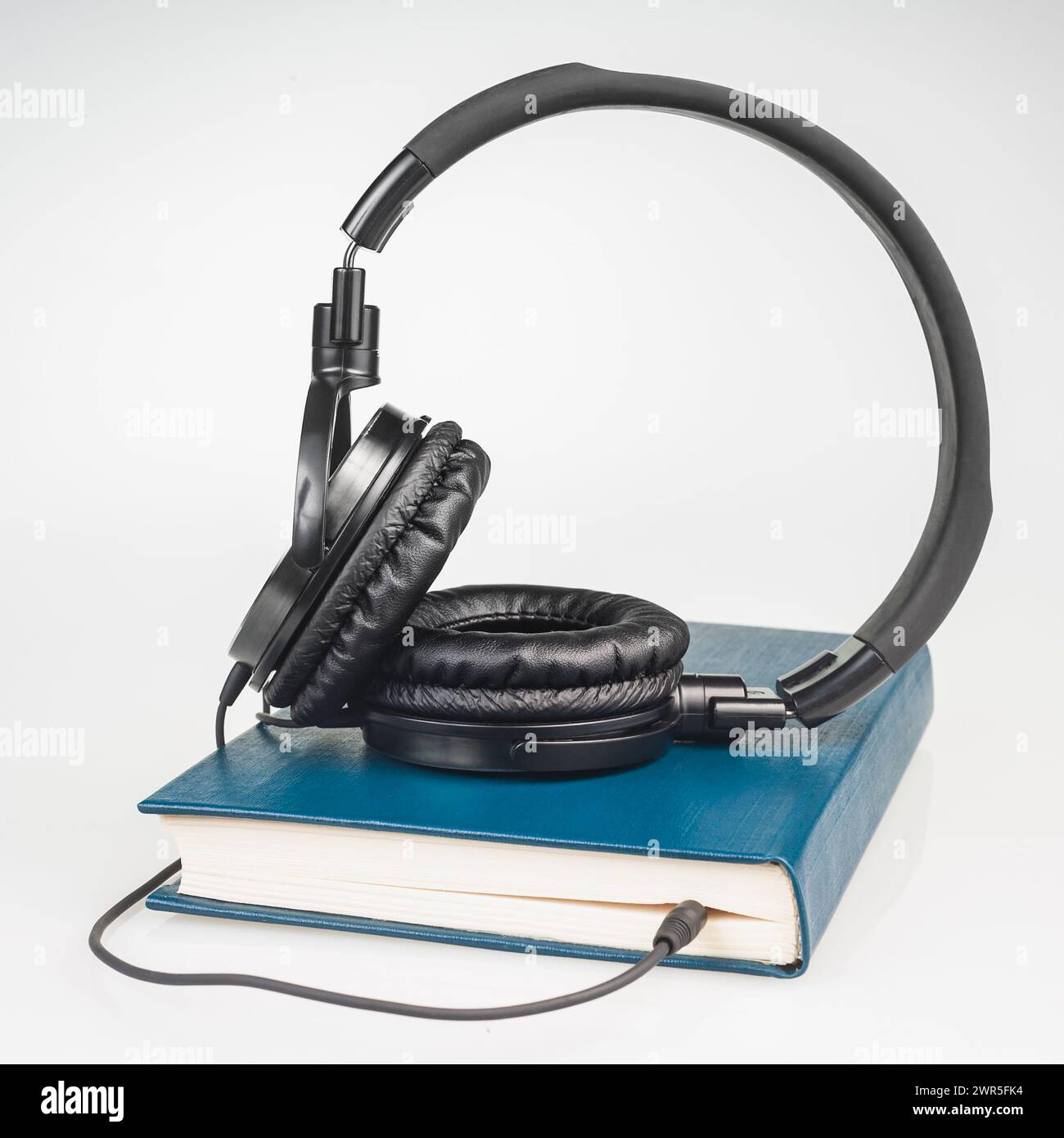 Headphones rest on a closed book symbolizing concept of audiobooks ...