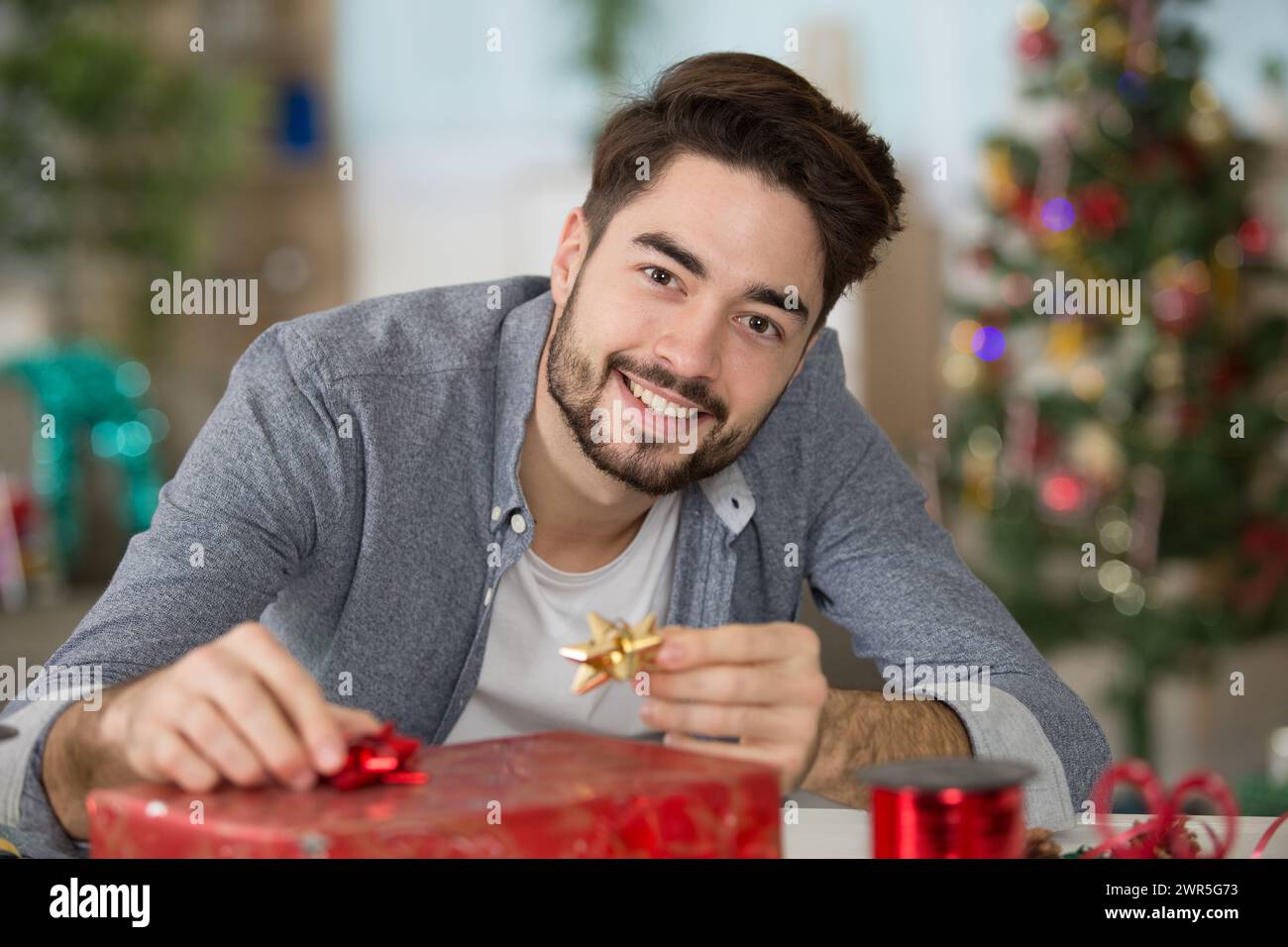 attentive man wrapping present in natural paper and rope Stock Photo ...