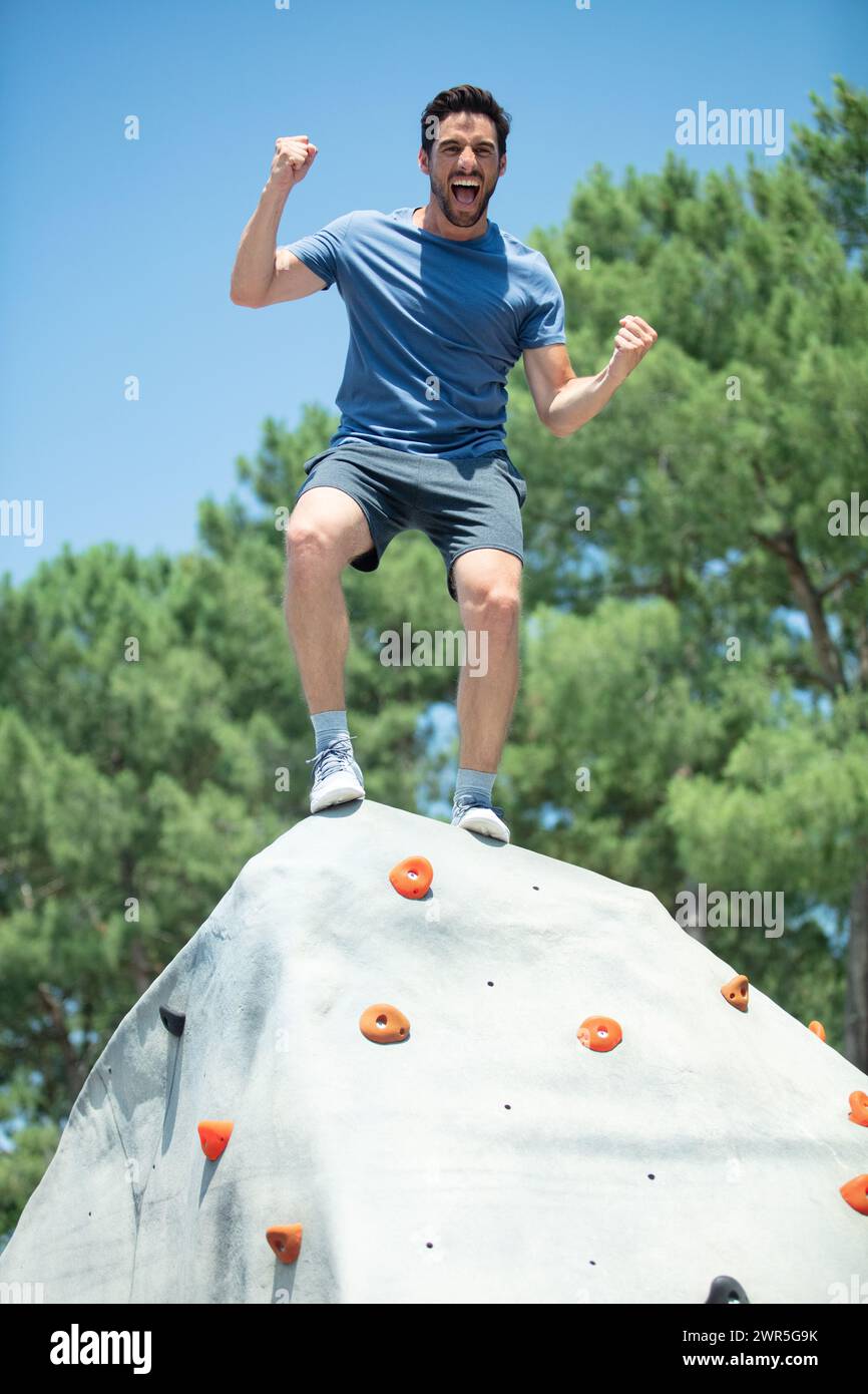 success concept - man climbing on edge showing victory Stock Photo - Alamy
