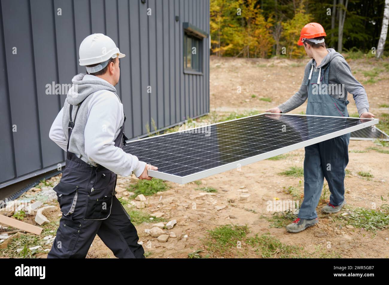 Mounters building solar panel system. Men workers in helmets carrying ...