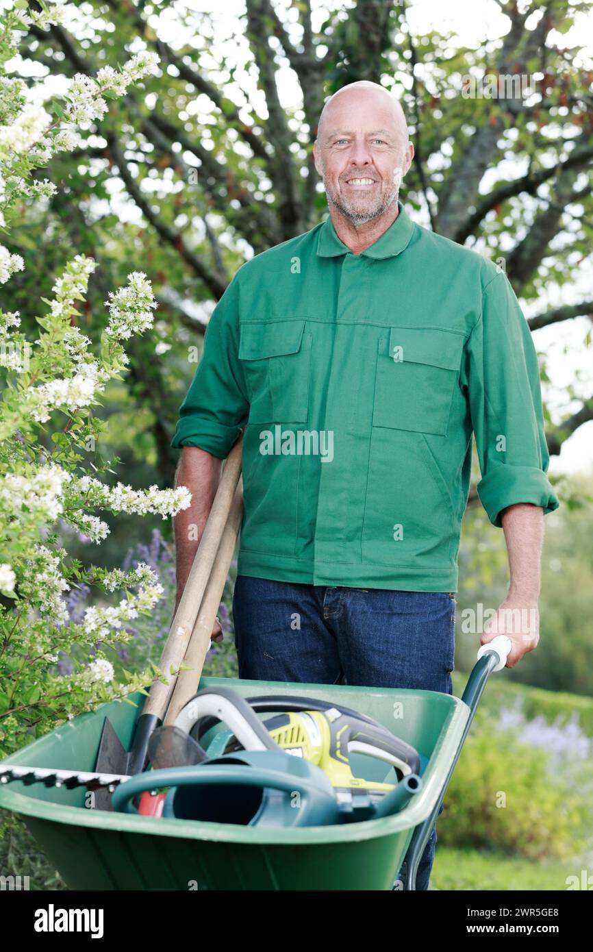 a happy gardener posing with a wheelbarrow Stock Photo - Alamy