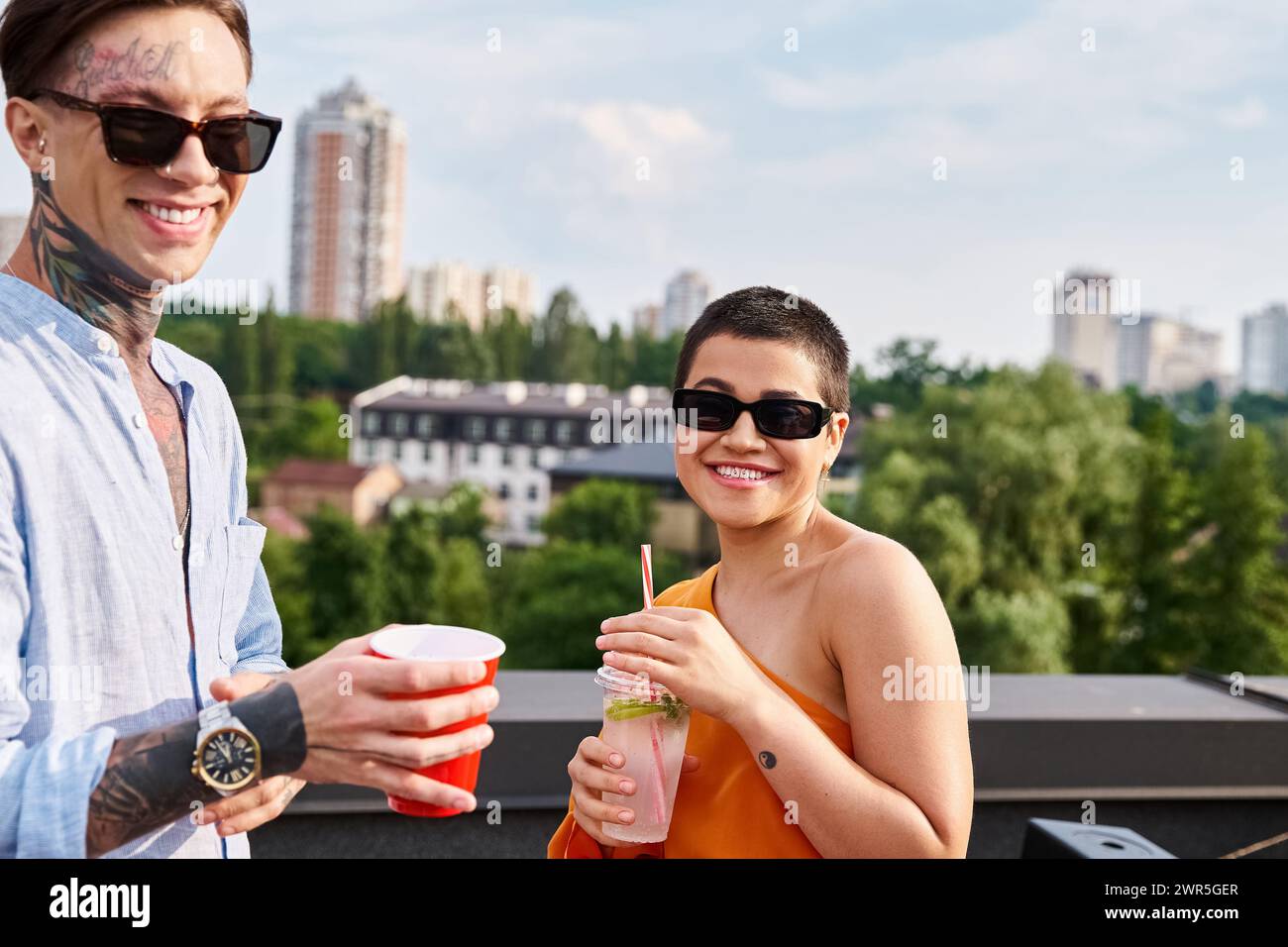 jolly man and woman in vivid attires with sunglasses drinking at ...