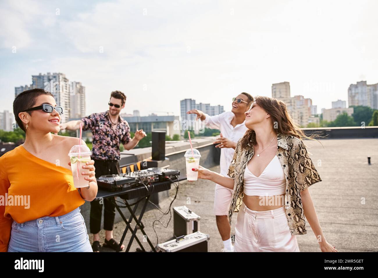 cheerful interracial friends with sunglasses drinking alcohol at ...