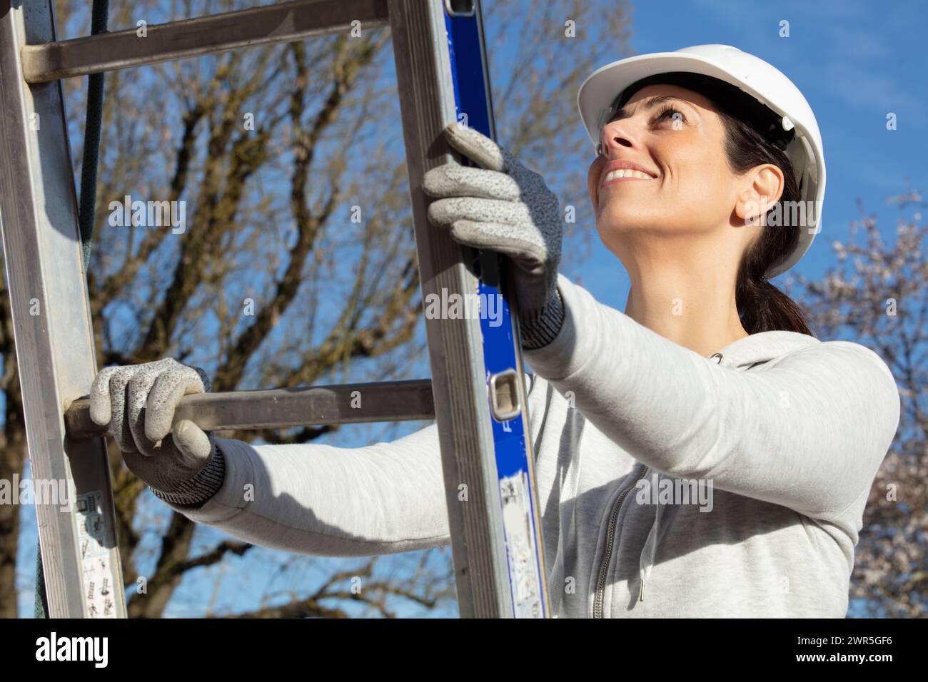 woman wearing safety helpmet holds a ladder outdoors Stock Photo - Alamy