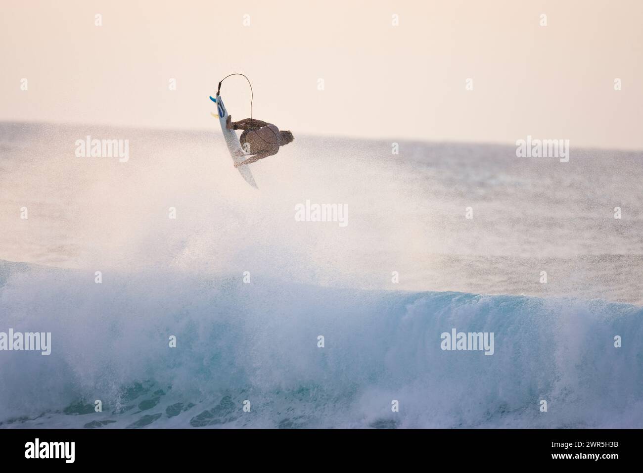 A young man completes an aerial flip maneuver while surfing at Rocky ...