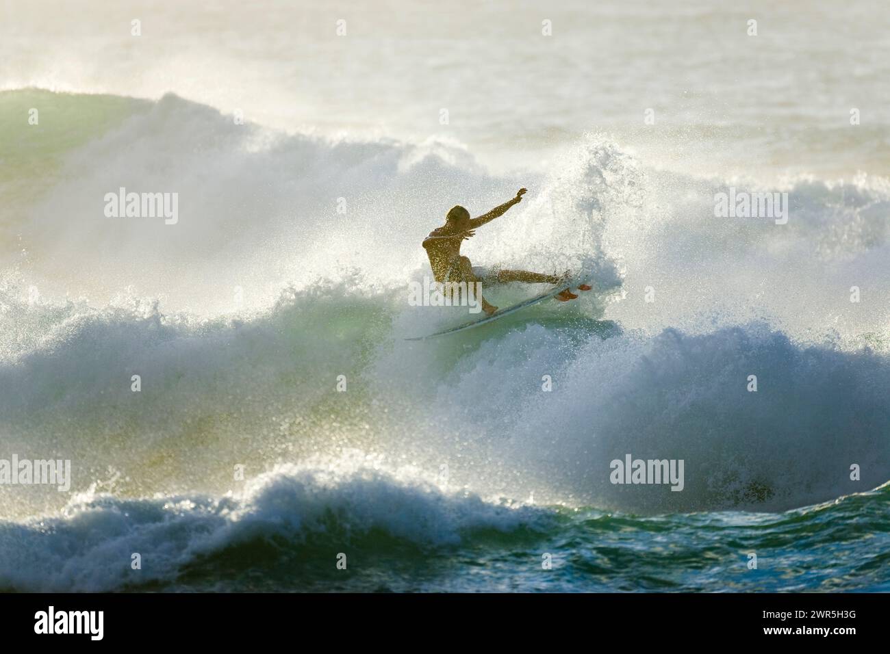 A young man performing an aerial maneuver while surfing at Rocky Point ...