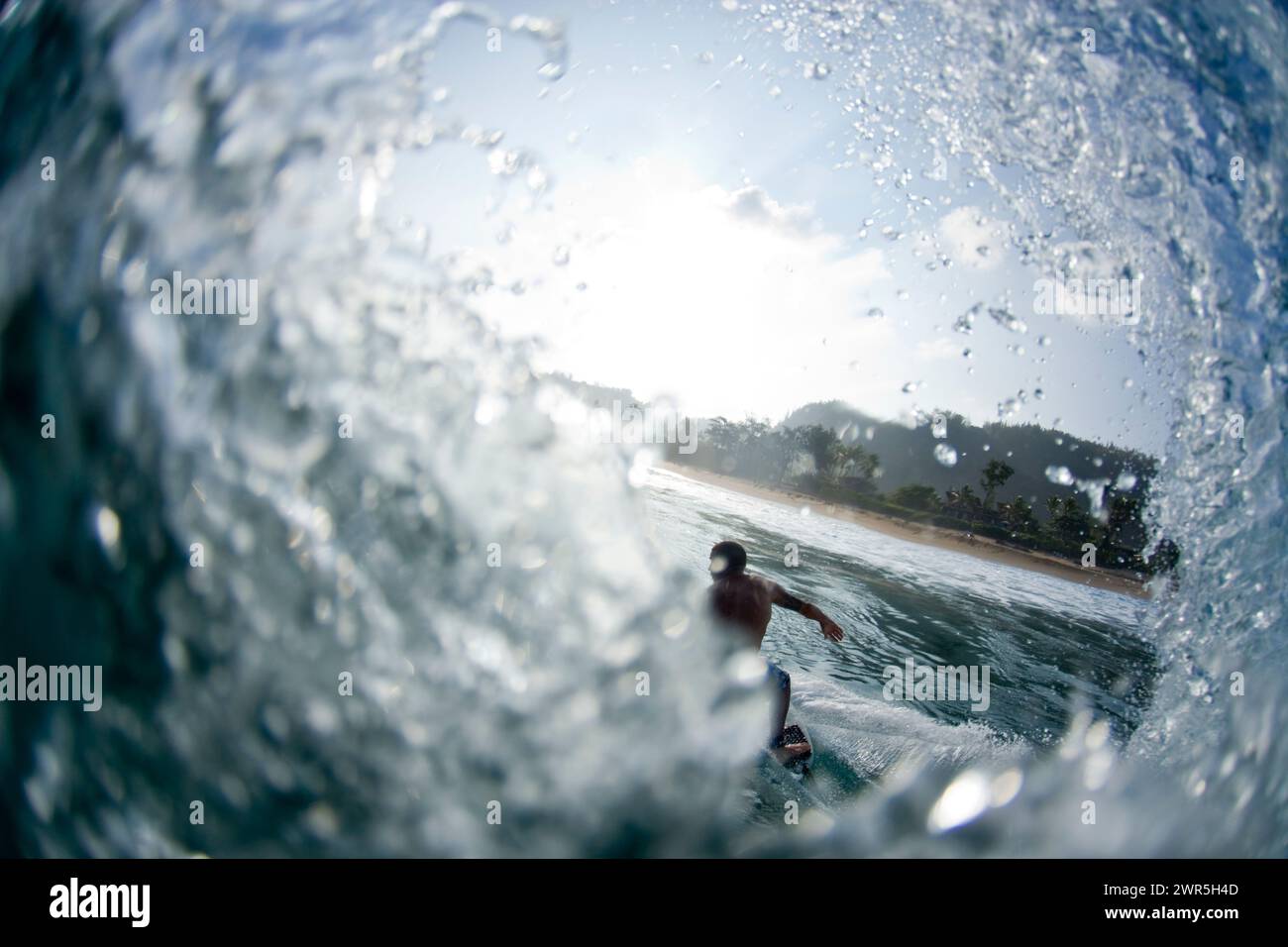 View from the water of a young man surfing in the tube at Rocky Point ...