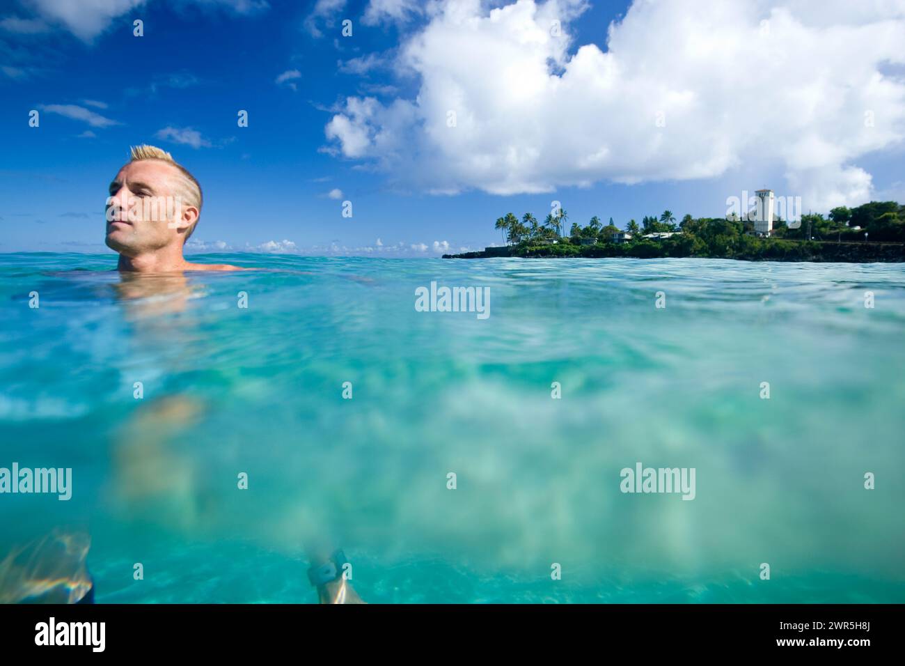 A split level, (under water / above water) view of young man swimming ...