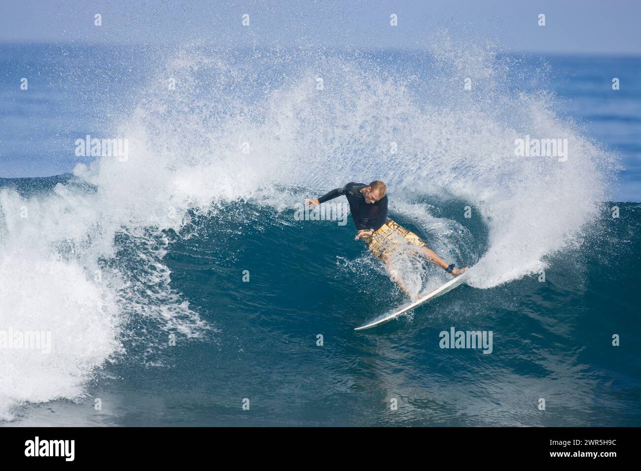 A young man surfing at Rocky Point on the north shore of Oahu, Hawaii ...