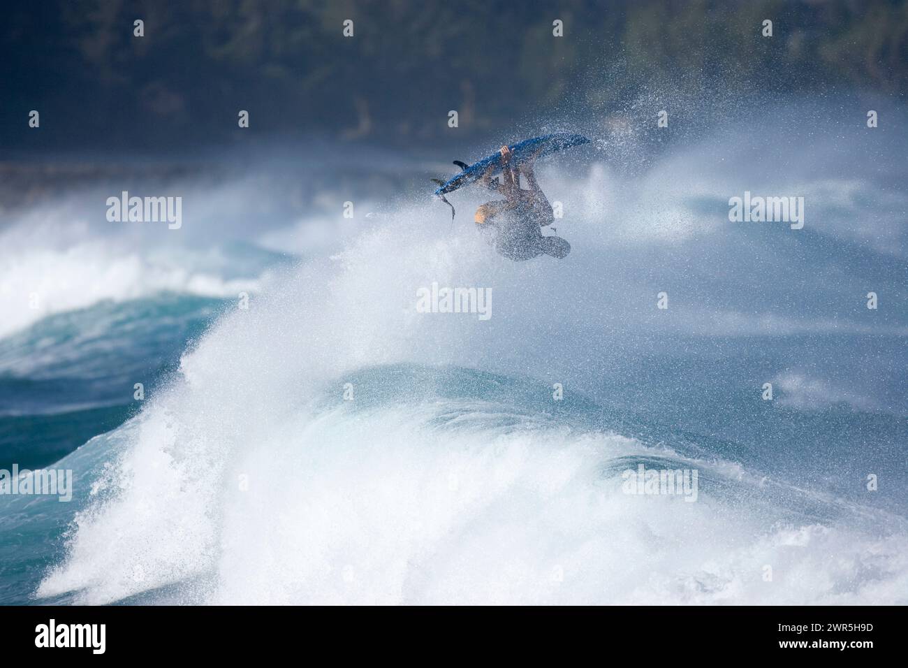 A young man performing an aerial maneuver while surfing at Turtle Bay ...