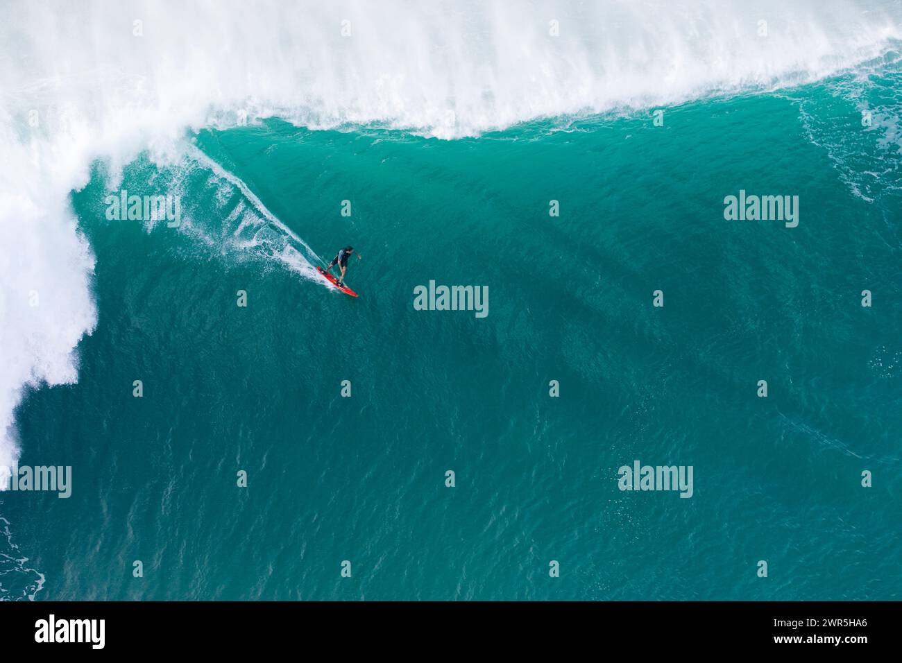 A young man tow surfing into a huge wave, on the north shore of Oahu ...
