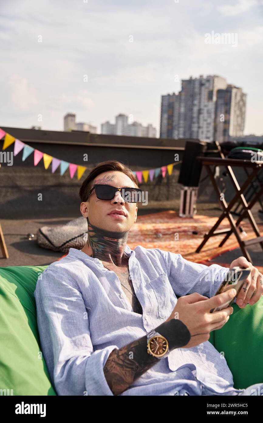 jolly handsome man with tattoos and sunglasses relaxing with phone in ...