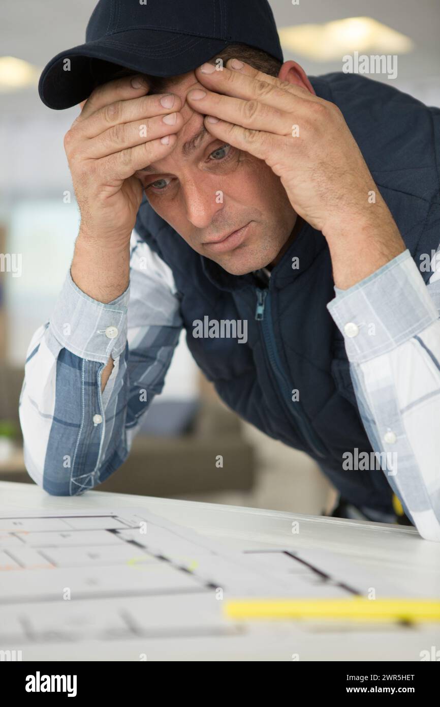 stressed builder worrying over blueprints Stock Photo - Alamy