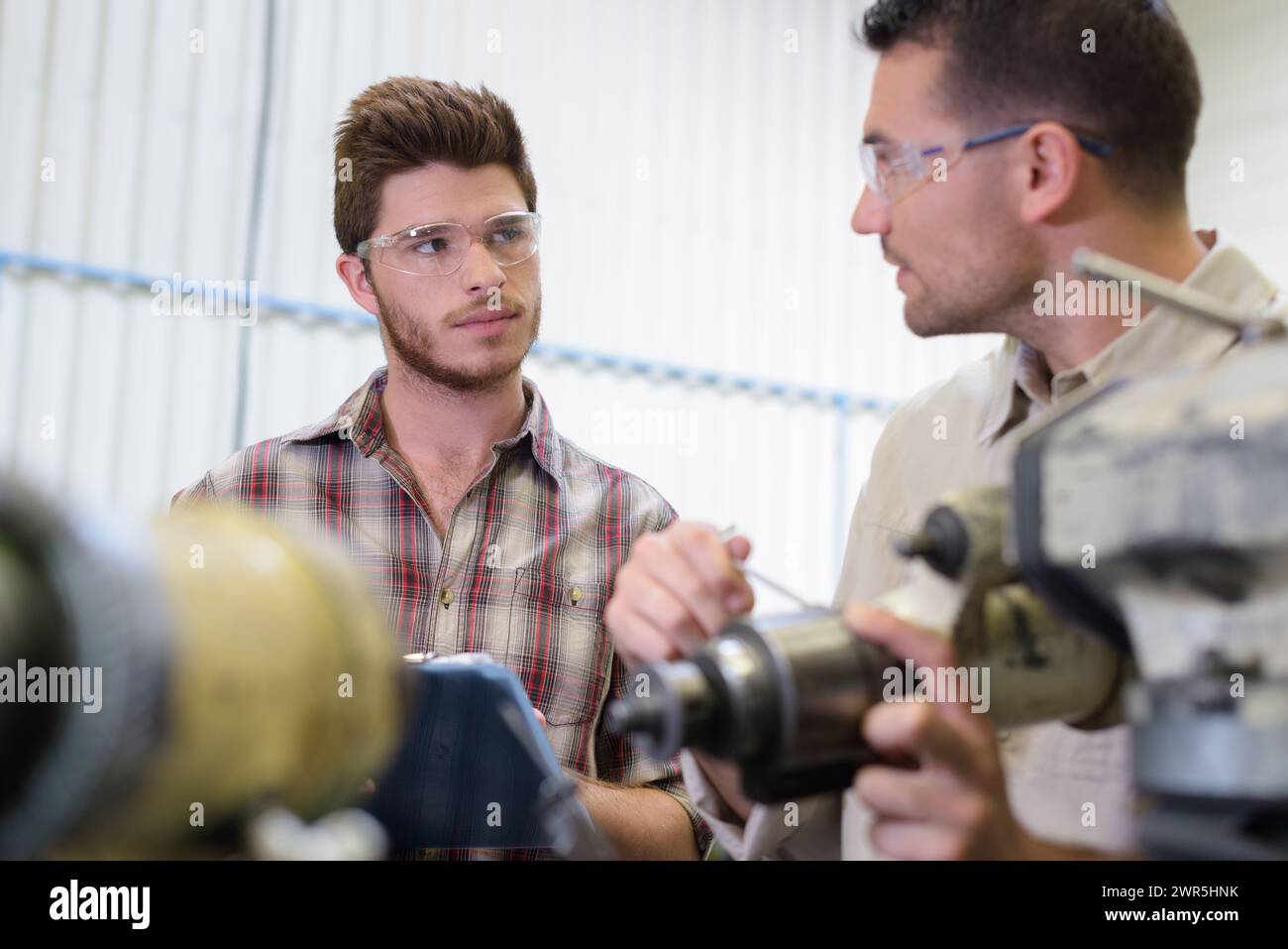 man showing working of machinery to apprentice Stock Photo - Alamy
