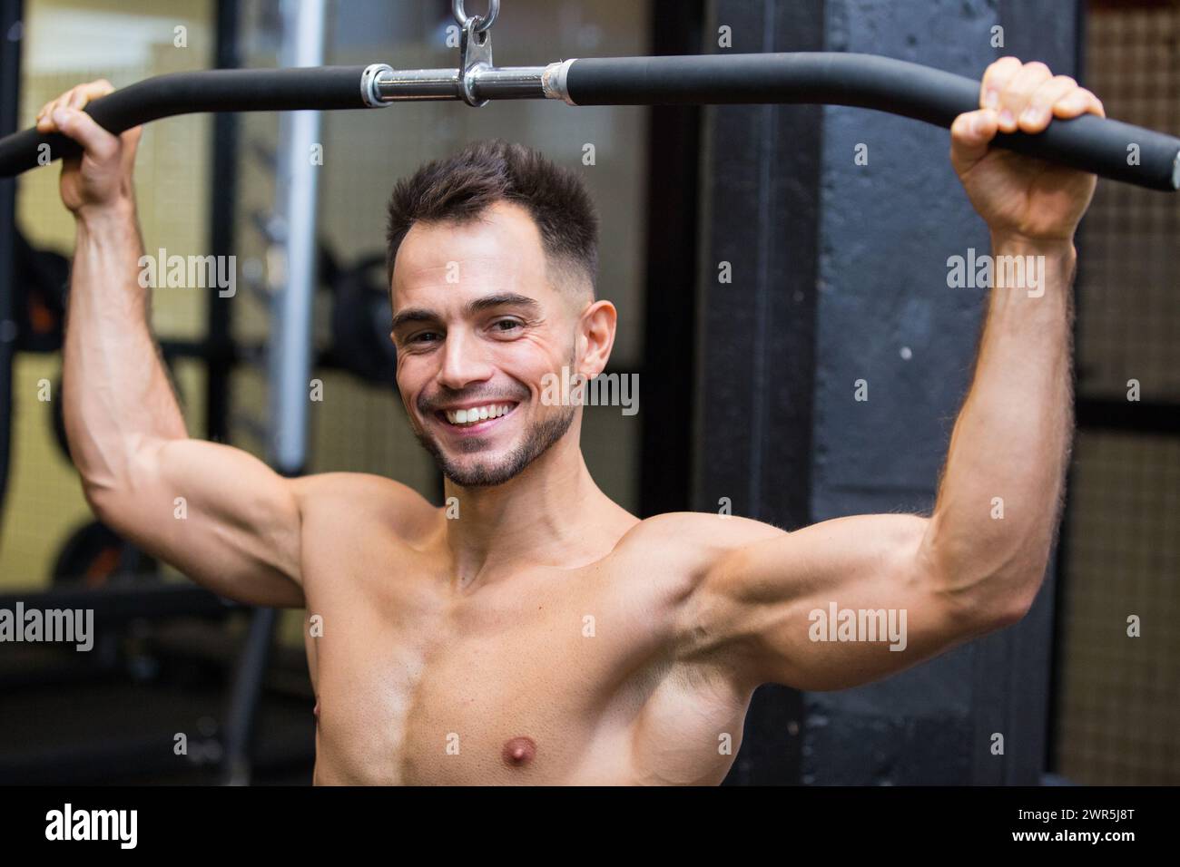 young smiling man lifting weights in gym Stock Photo - Alamy