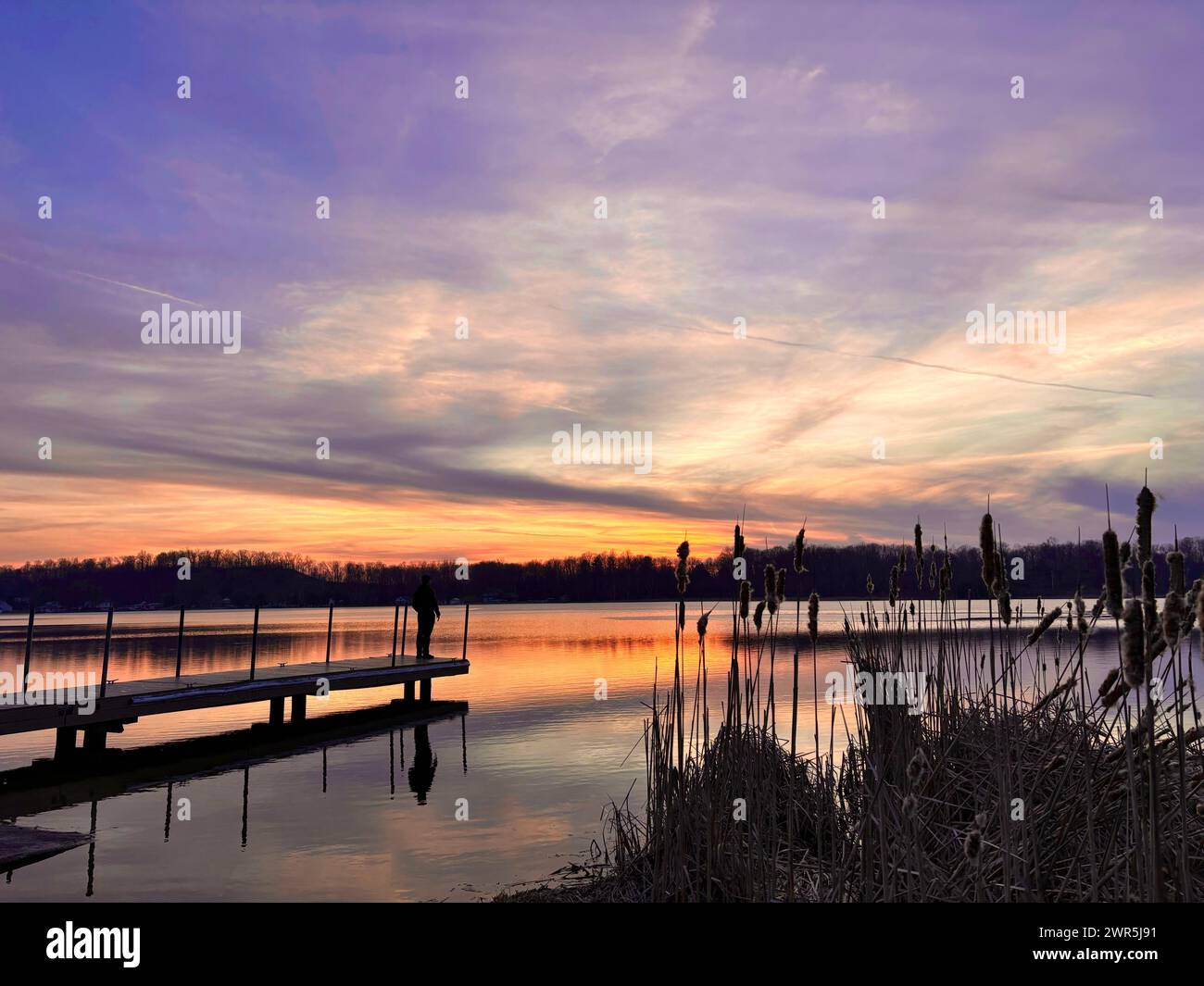Man standing on the dock staring out to lake with sunset Stock Photo ...