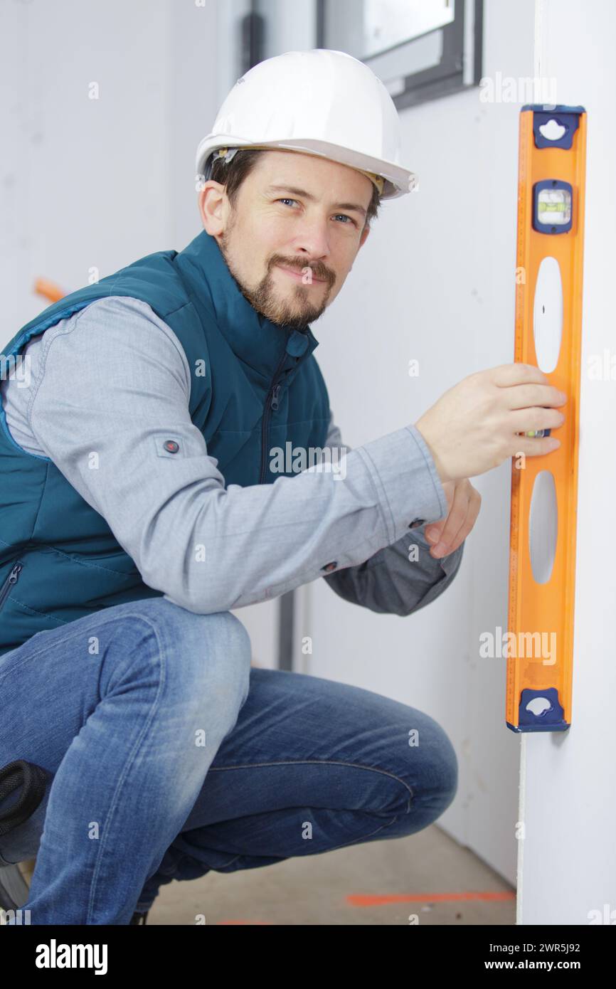 professional worker in helmet is measuring wall with level Stock Photo ...