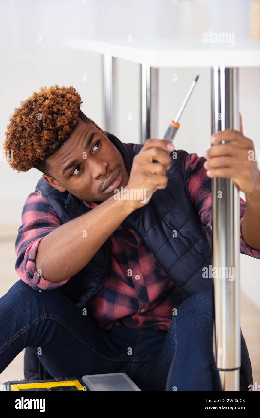 handsome young man using screwdriver for fixing table Stock Photo - Alamy