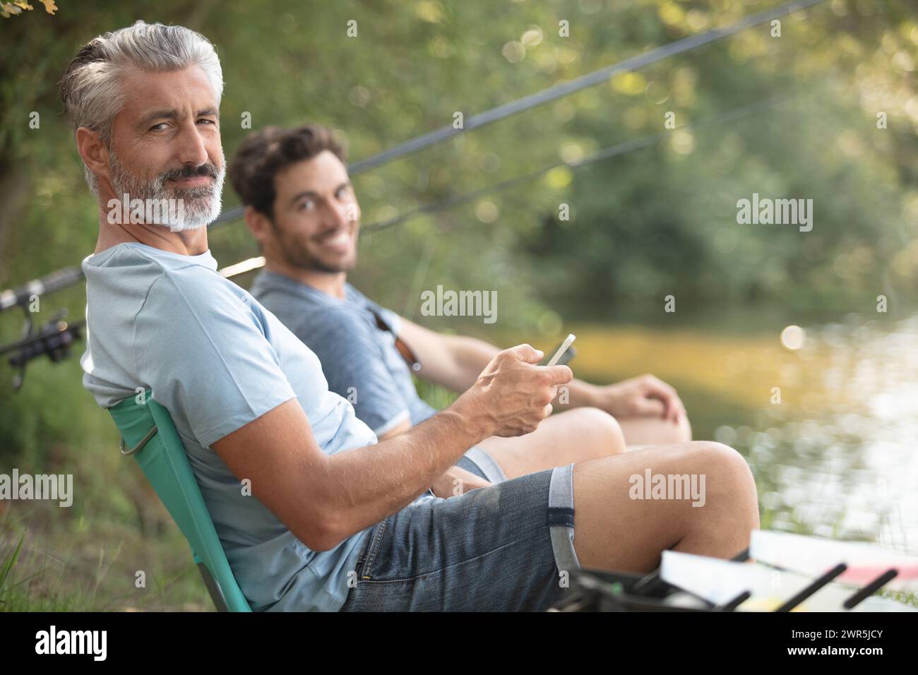 men fishing standing on lakeshore Stock Photo - Alamy