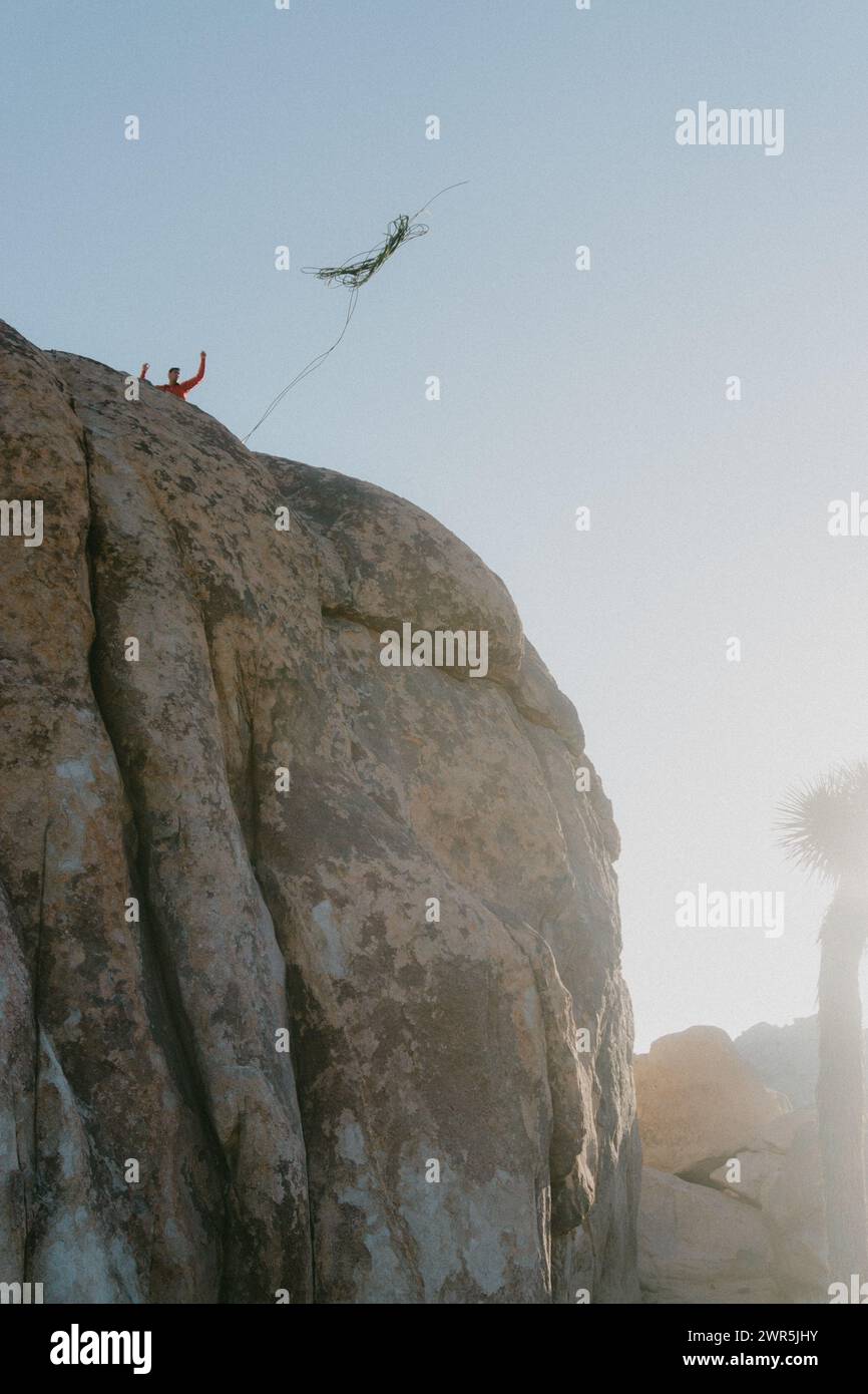 Man throwing down climbing rope off top of rock in Joshua Tree Stock ...