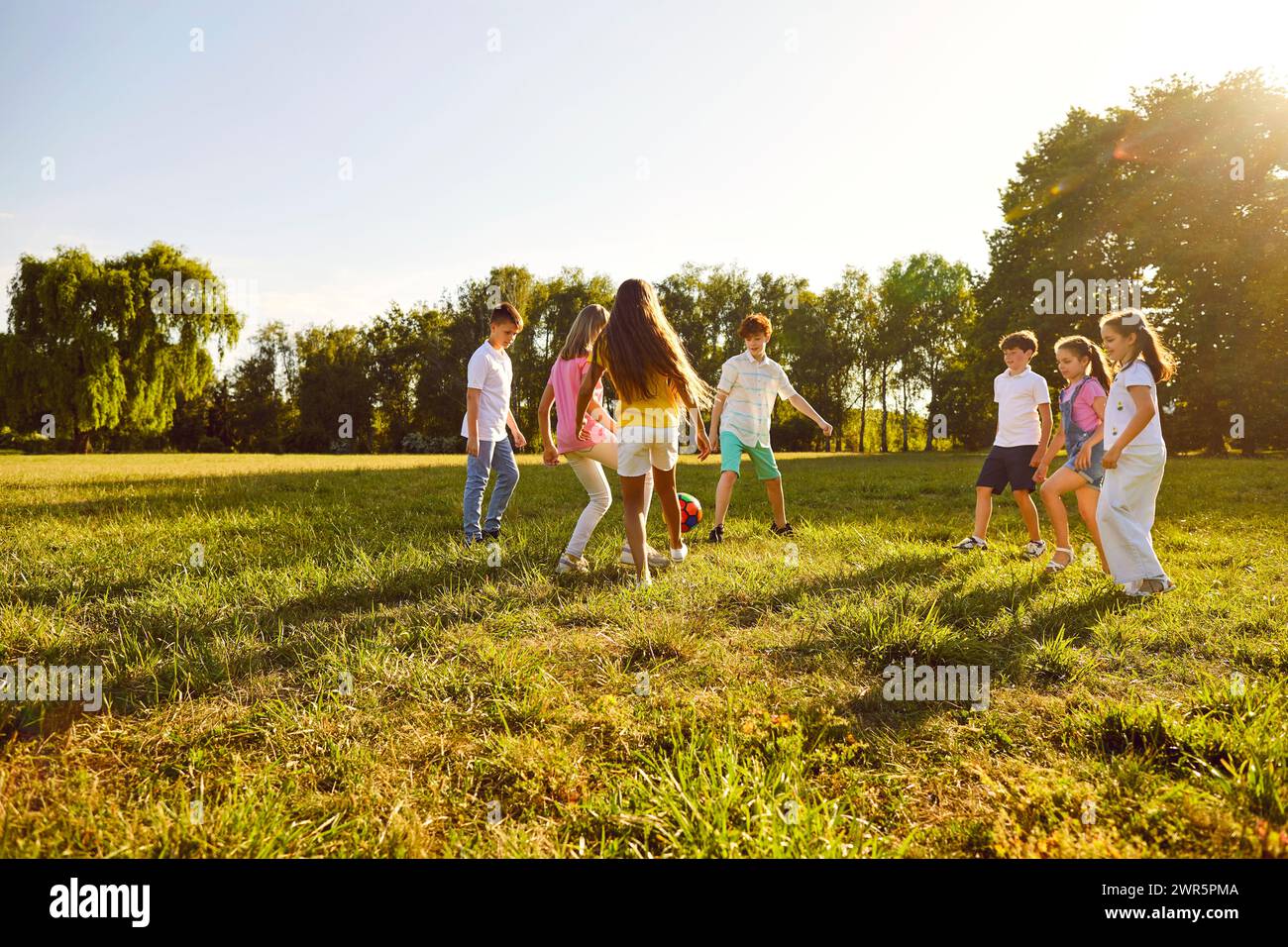 Happy children boys and girls running towards ball playing together on ...