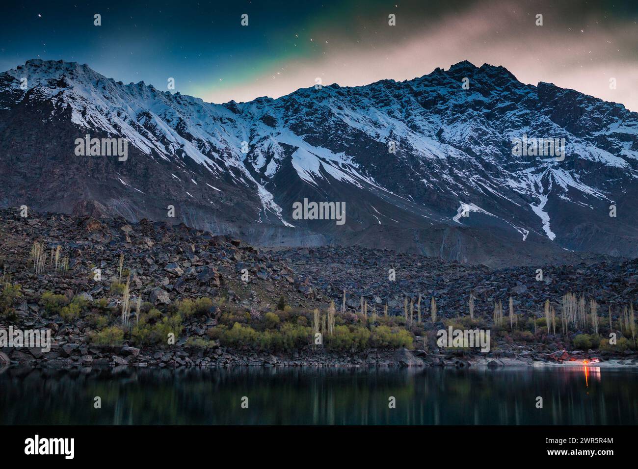 Northern lights dance above snow-capped mountains, providing a ...