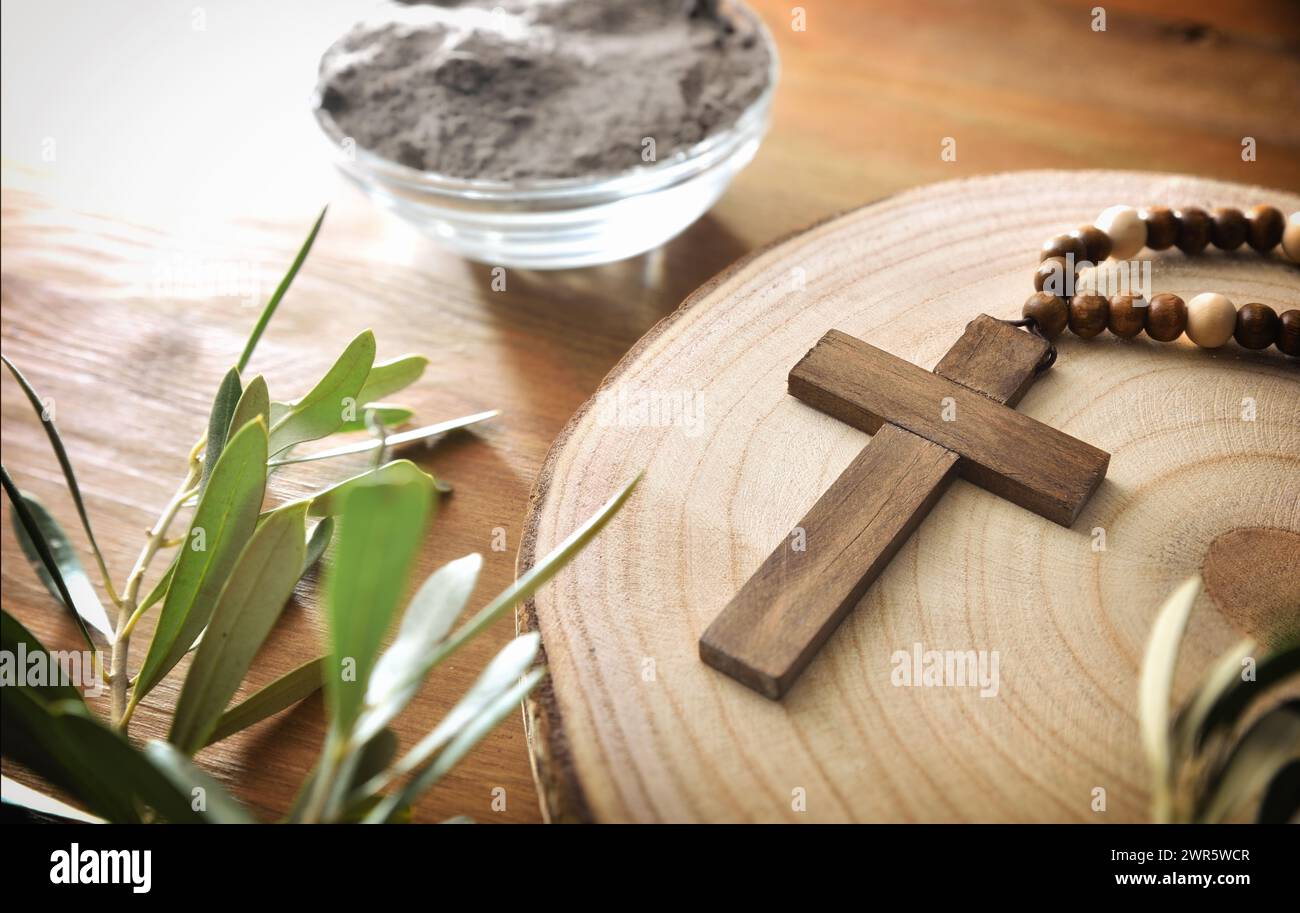 Christian cross on wooden base on a table with olive leaves and ...