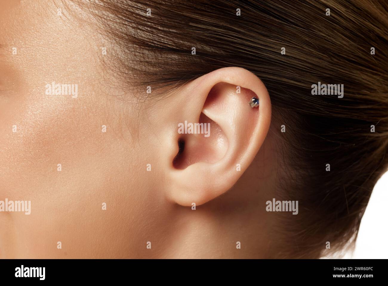 Close up photo of female ear with piercing against white studio ...